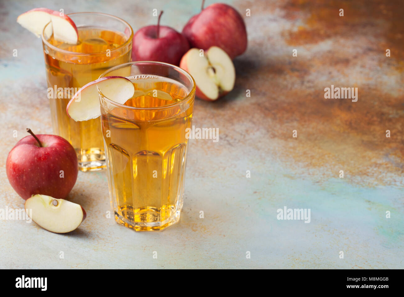 Two glasses of red Apple juice with mint and ice on an old rusty table ...