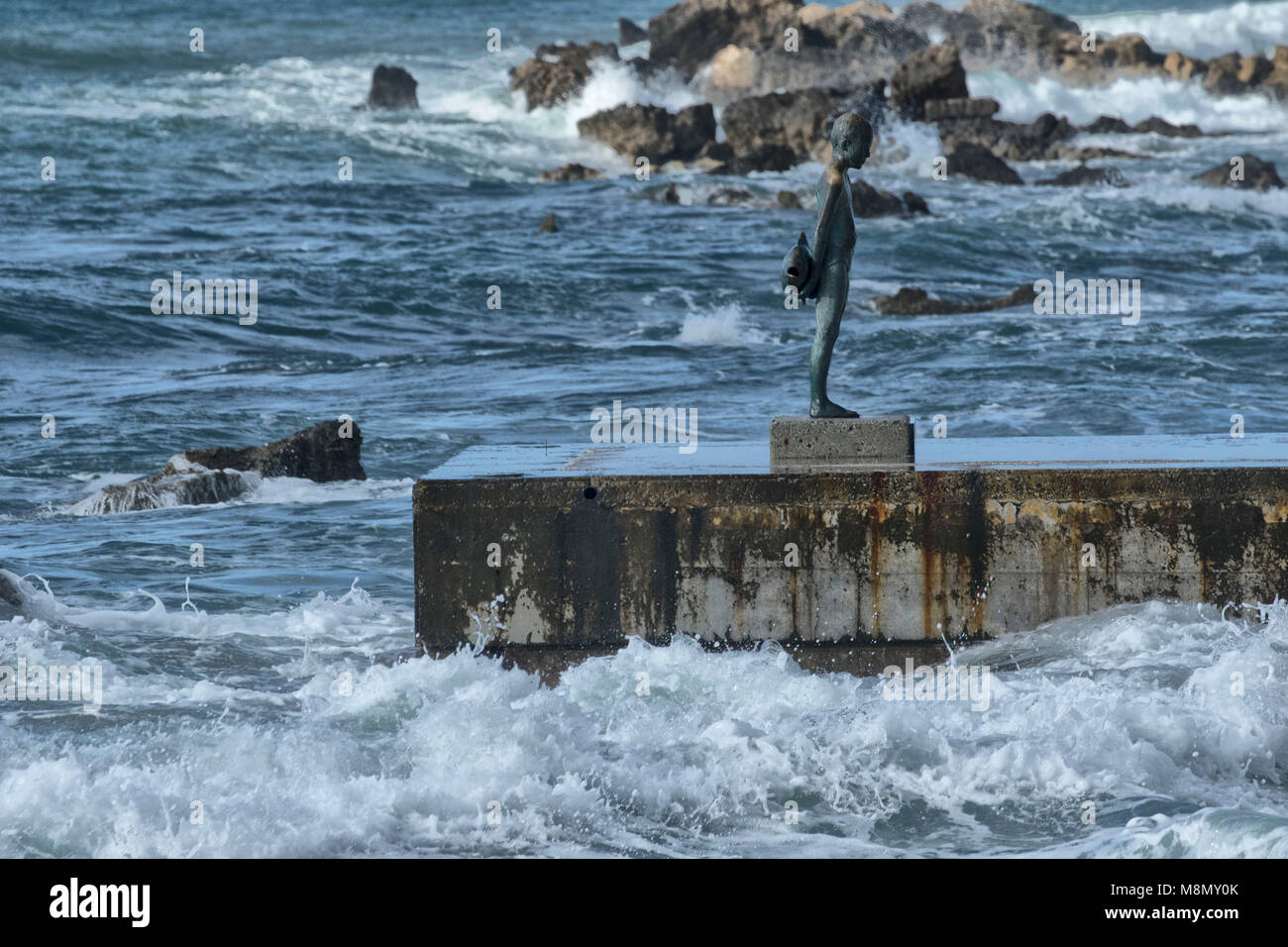 Statue of boy with fish in rough mediterranean seas in Paphos harbour ...