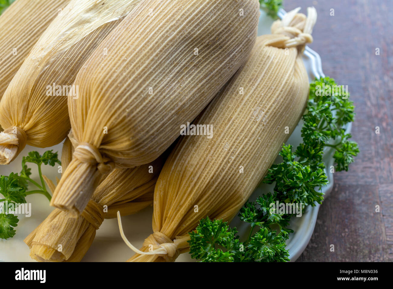 Close-up crop on unwrapped stacked Mexican tamales on wooden table ...