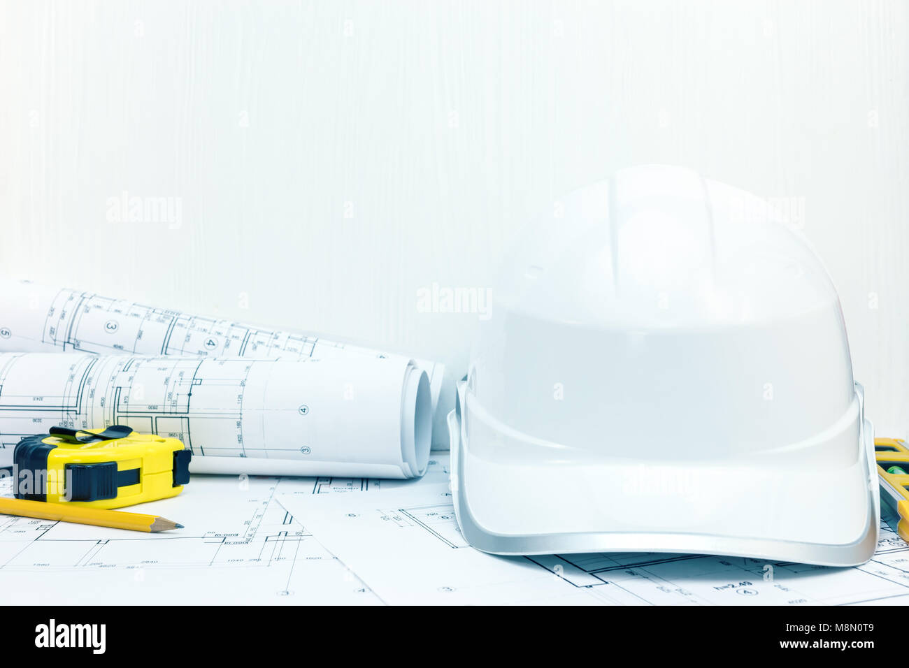 protective helmet, blueprint rolls and engineering instruments on table ...