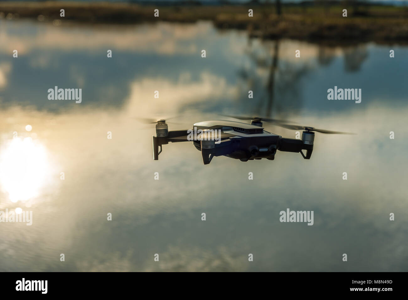 Small modern drone taking picture of lake at sunset Stock Photo - Alamy