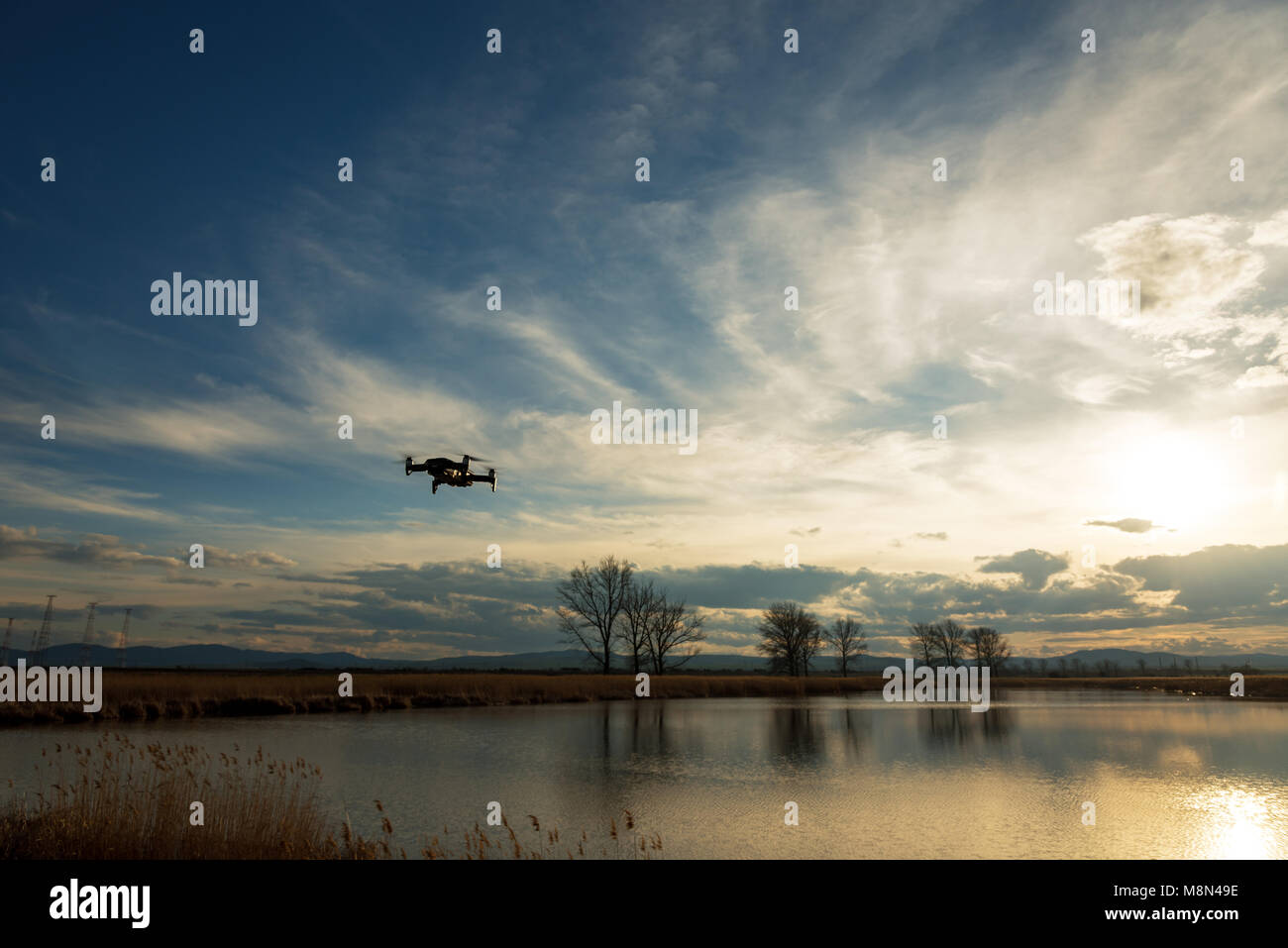 Small modern drone taking picture of lake at sunset Stock Photo - Alamy