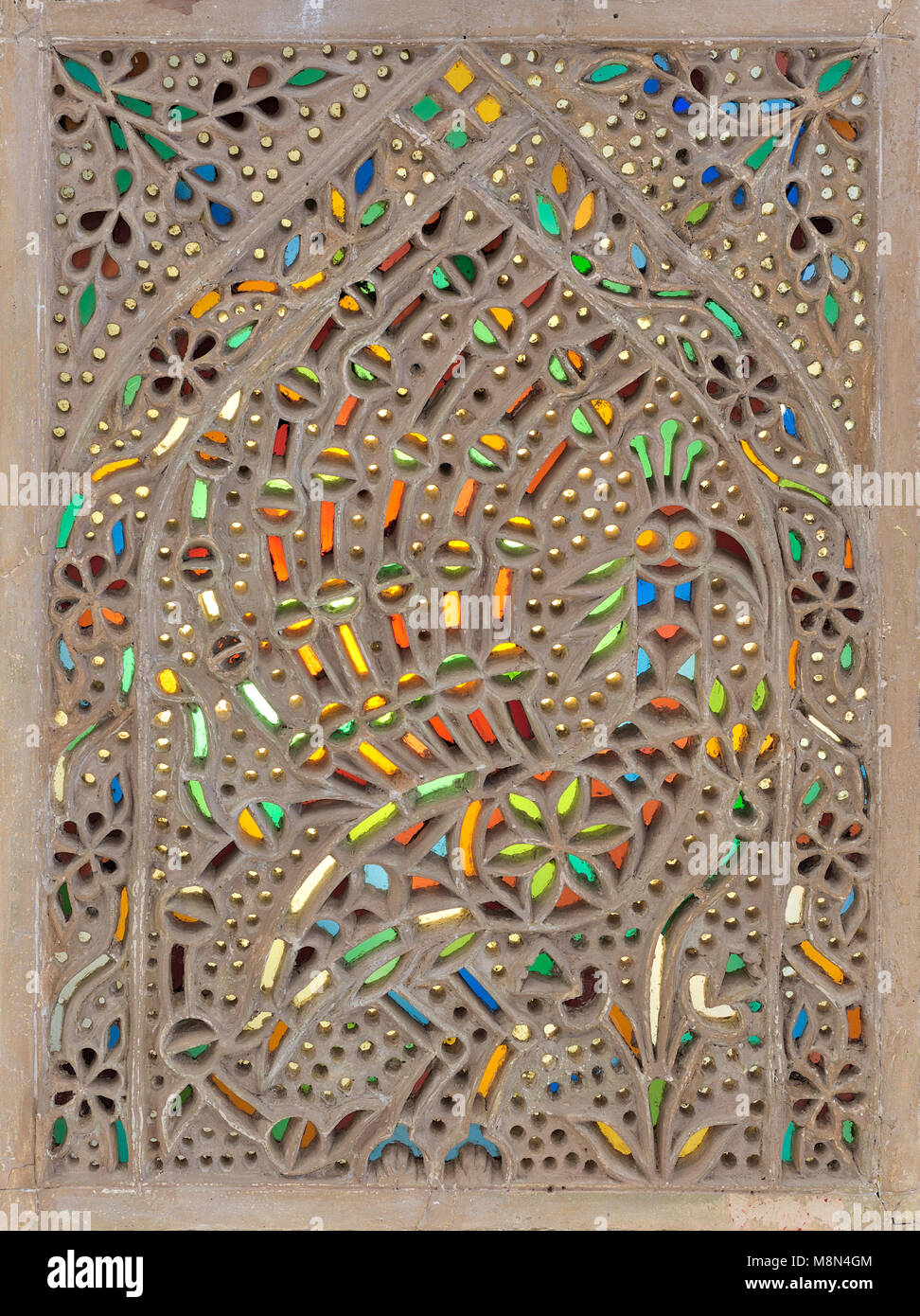 Perforated stucco window decorated with colorful stain glass with ...