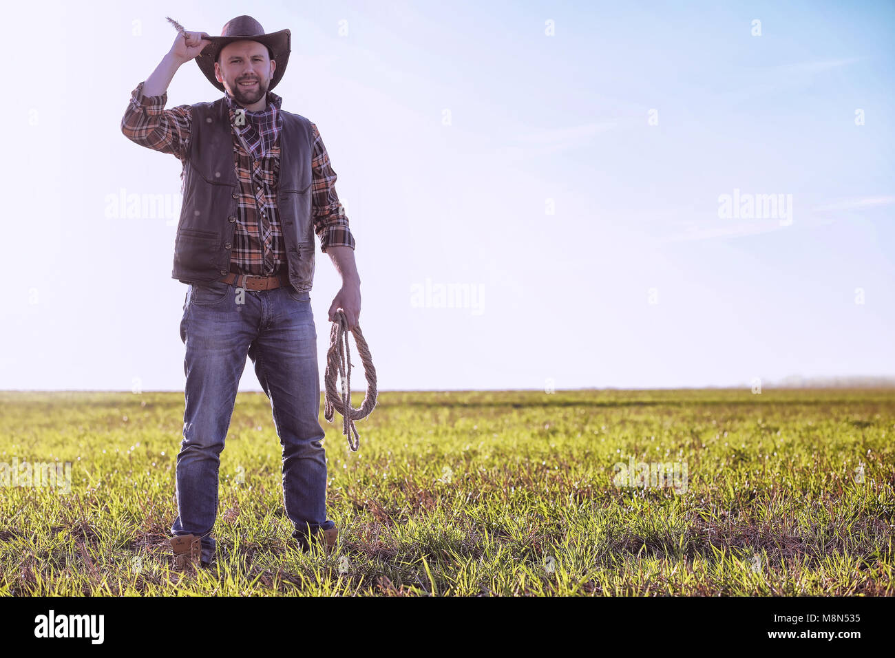 Cowboy standing in a field at sunset Stock Photo - Alamy
