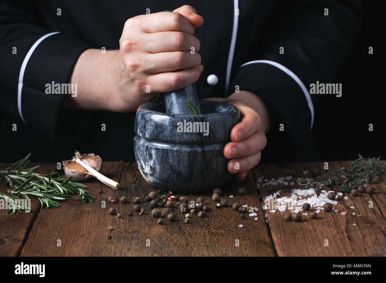 Woman chef pounding spices and herbs in mortar for food cooking on a ...