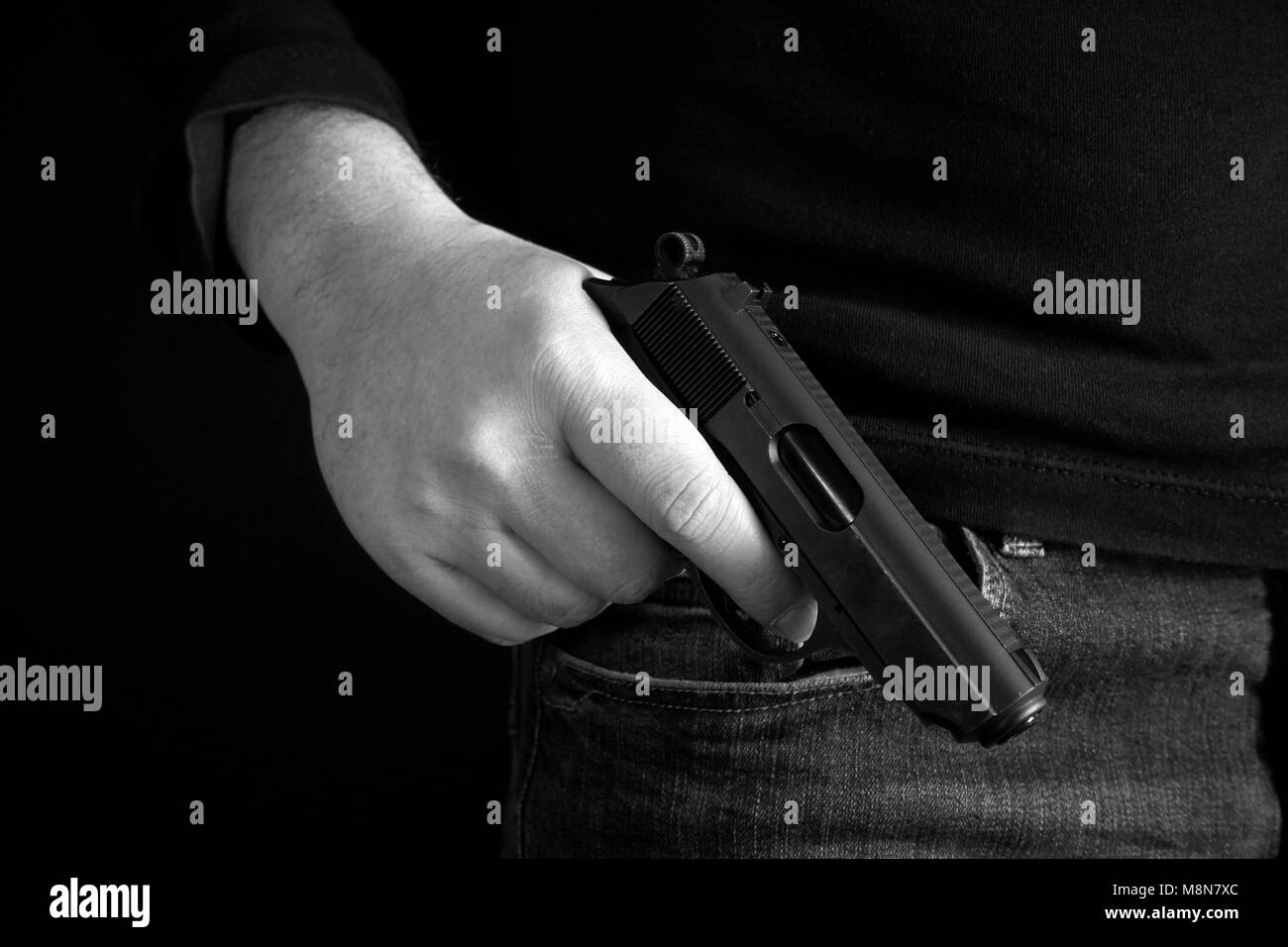 Mafioso holds pulled out gun, isolated on dark background back and ...
