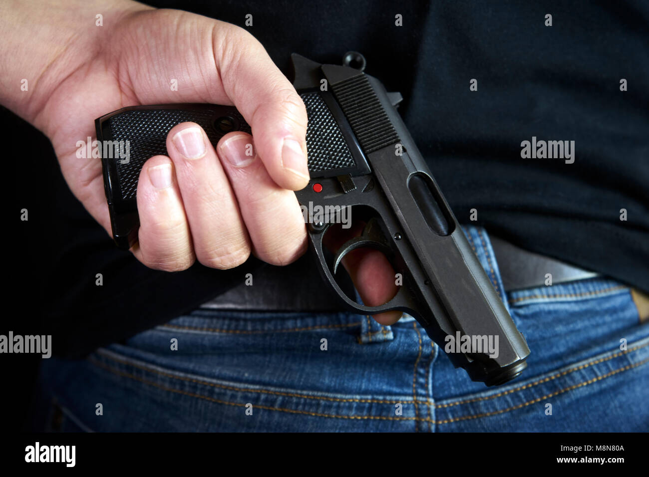 Hidden gun in hands back side to man in blue jeans Stock Photo - Alamy