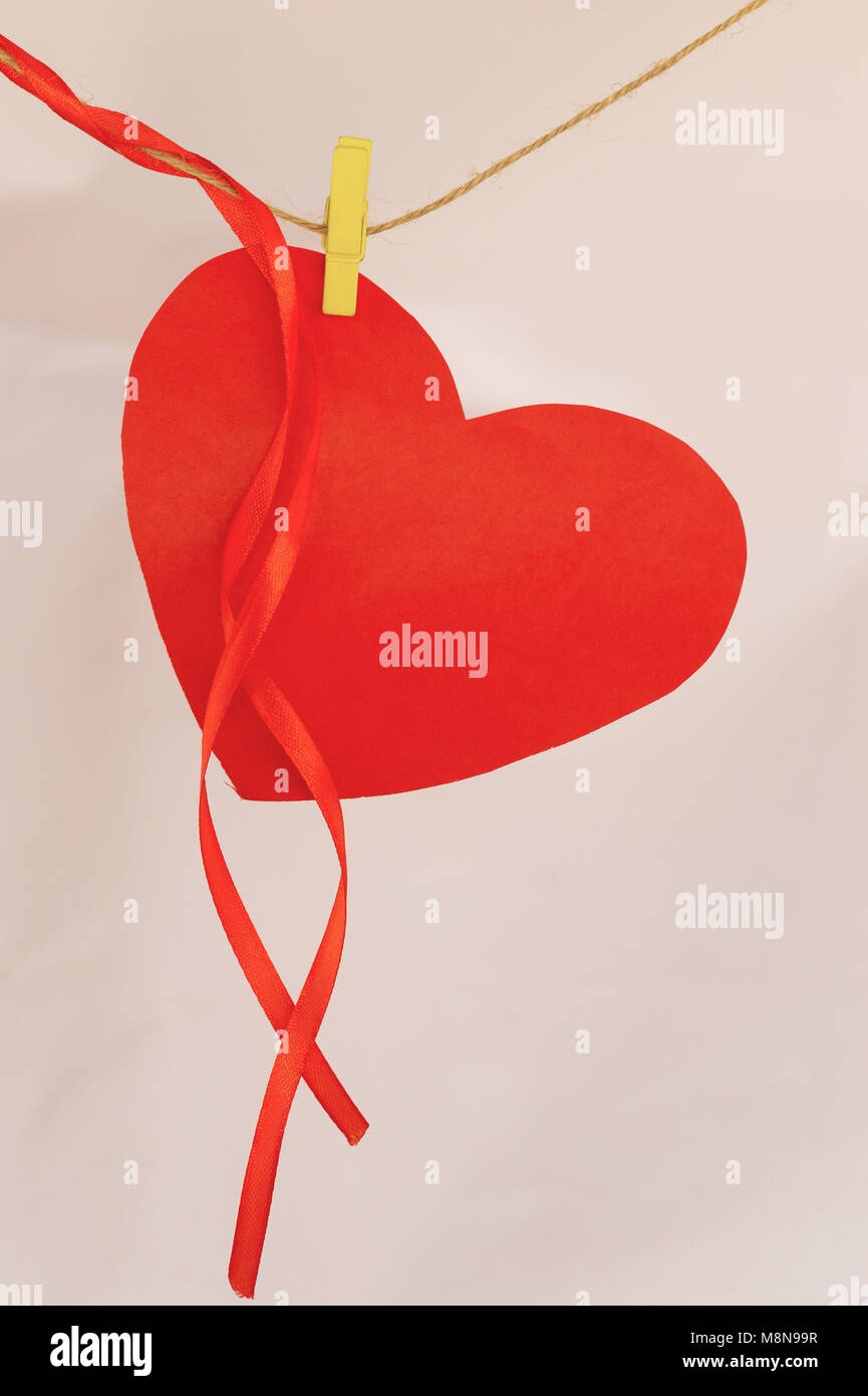 Red paper heart shape hanging on cloth line close view Stock Photo - Alamy