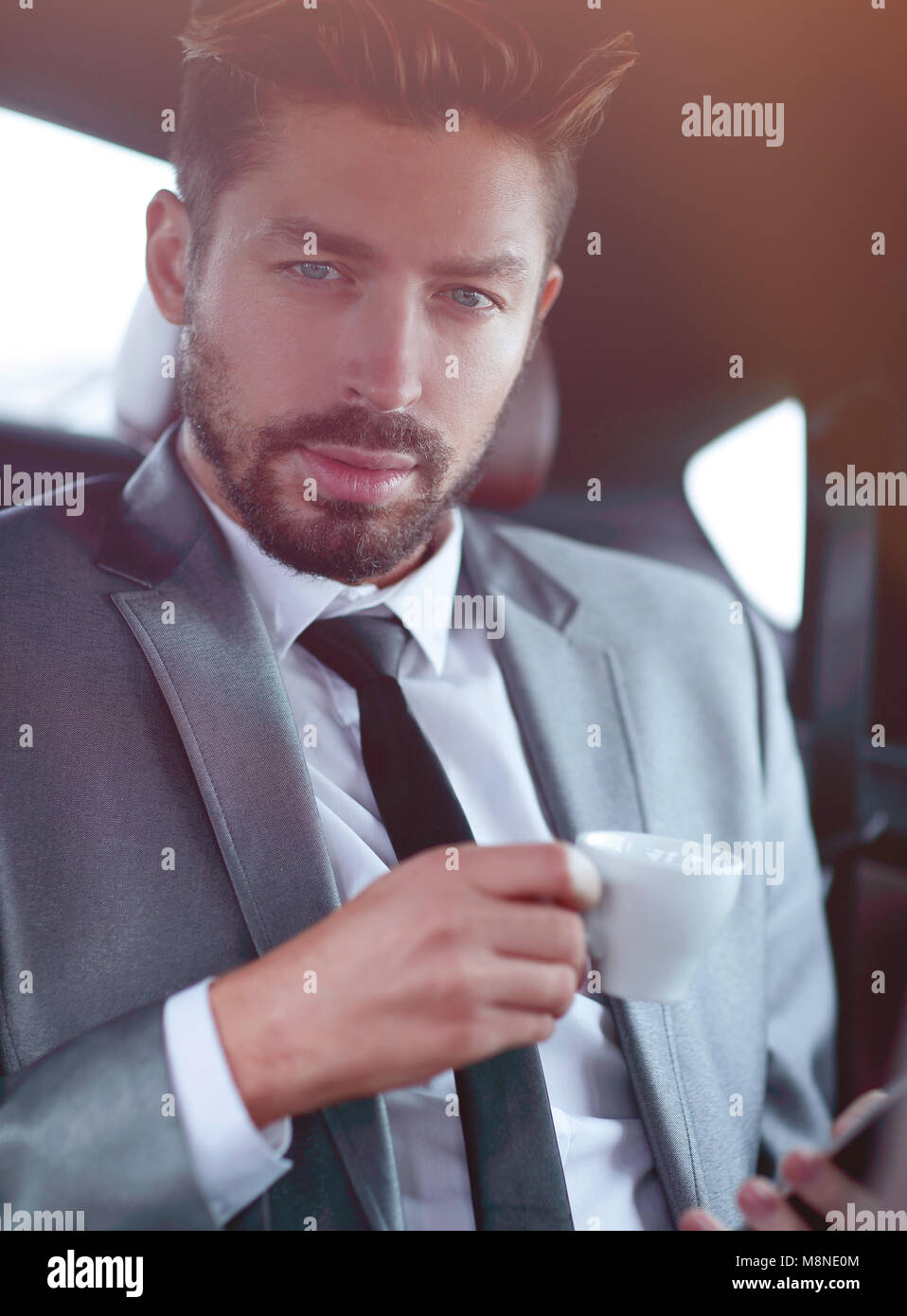 Businessman drinking coffee in the back seat of a car Stock Photo - Alamy