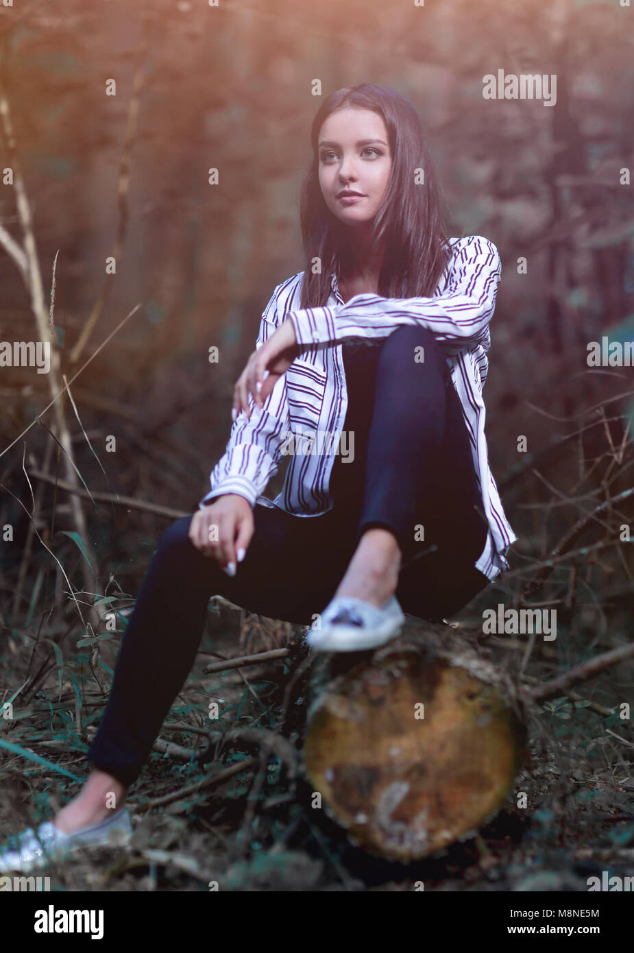 beautiful young woman sitting on a log Stock Photo - Alamy