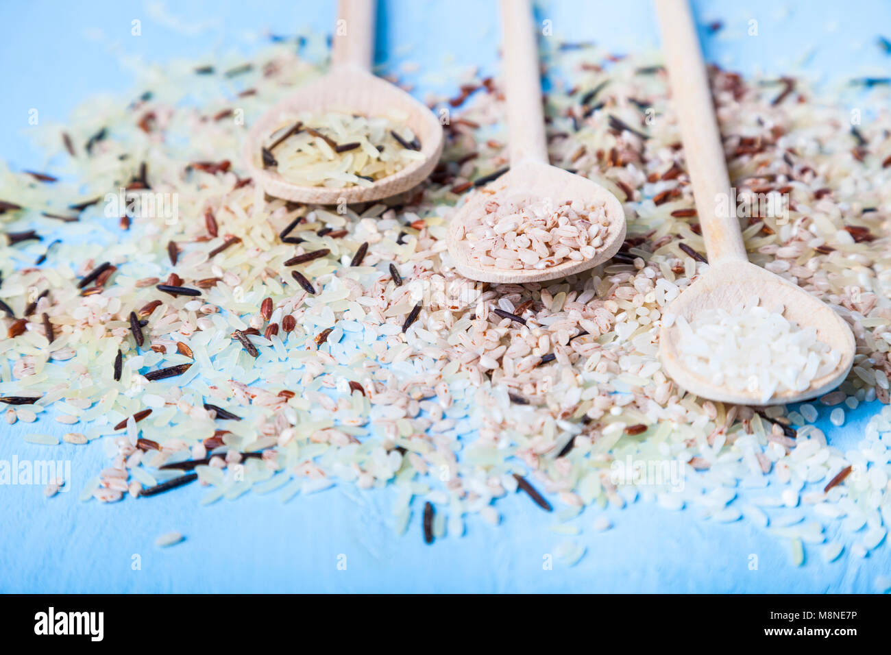 Three spoons with different grades of rice on an old wooden background ...
