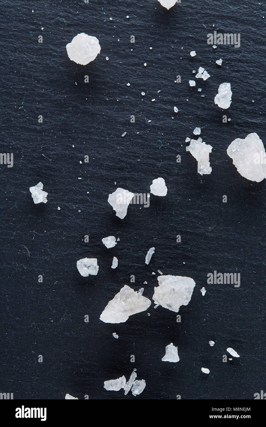 Pile of salt crystals isolated on the dark board over white textured ...