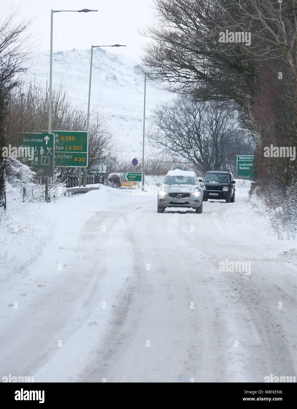 Cars are driven along a snow covered road near Okehampton in Devon. The ...