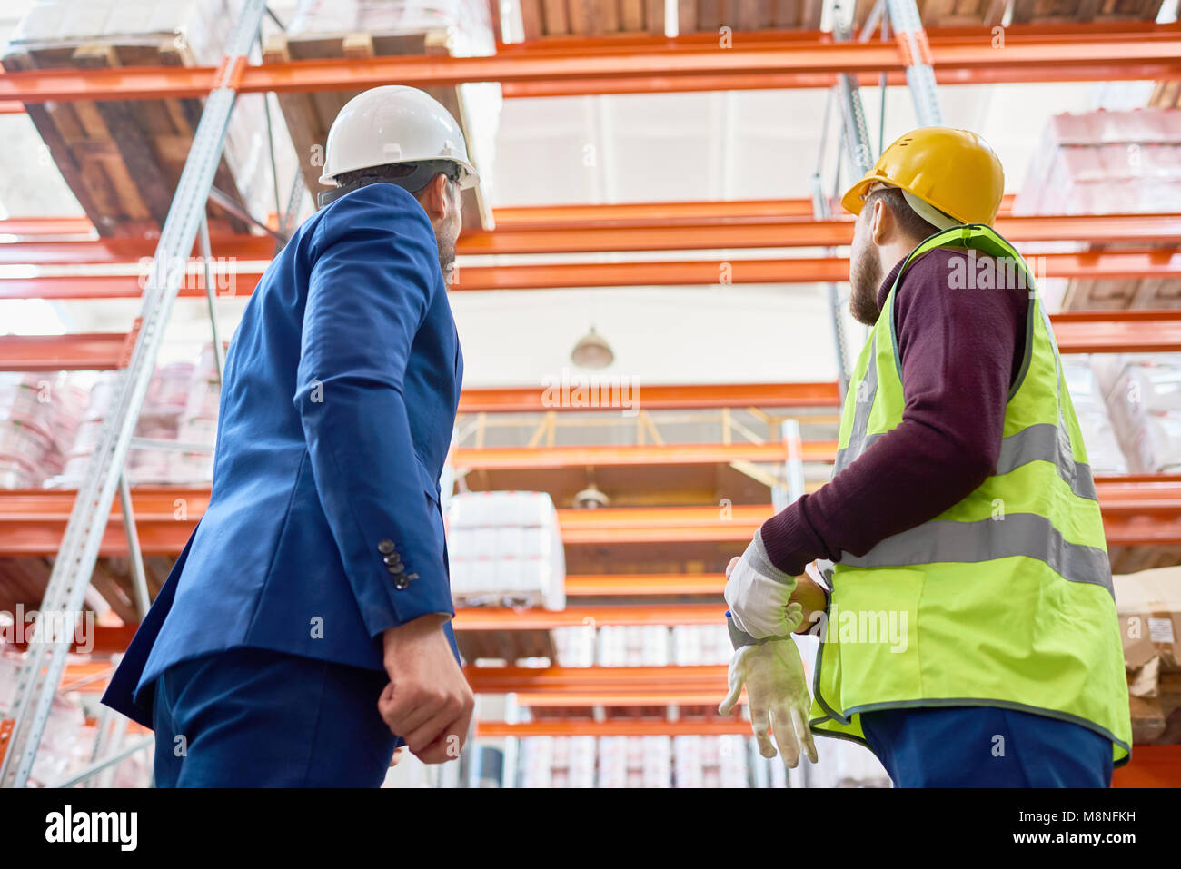 Back view low angle portrait of warehouse manager and factory worker ...