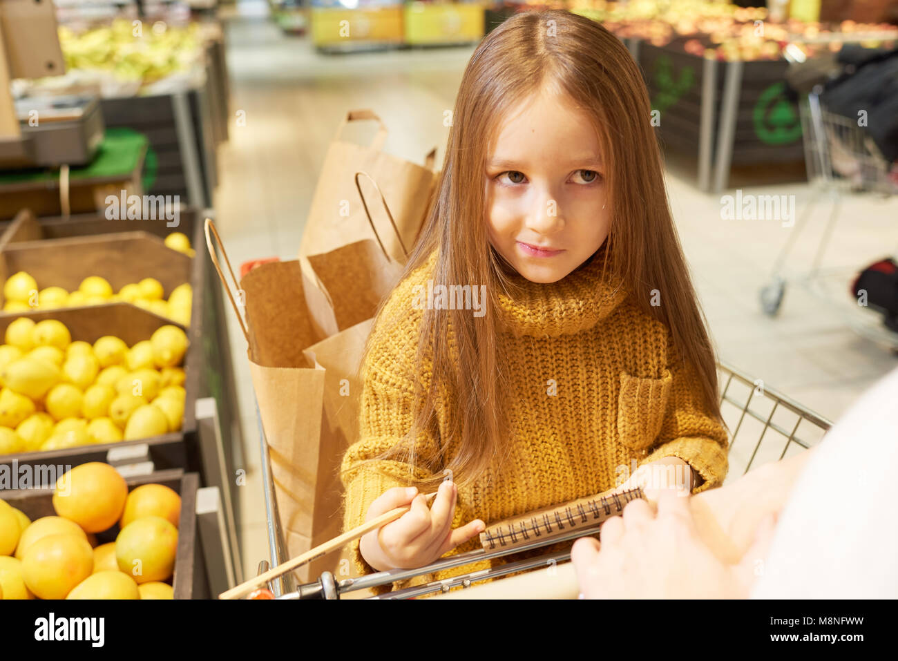 Portrait of cute little girl holding shopping list and ticking off ...