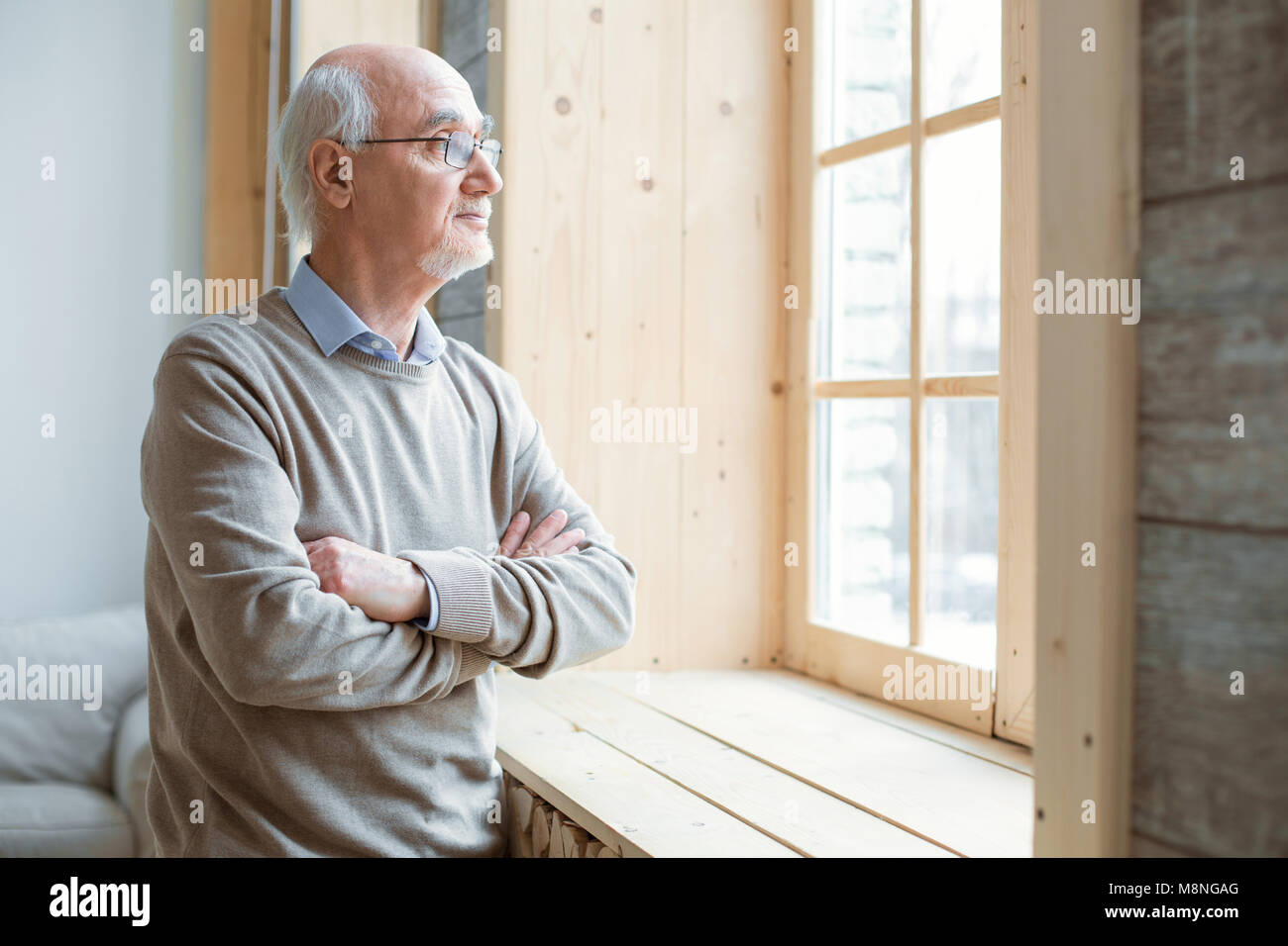 Medicative senior man staring through window Stock Photo - Alamy