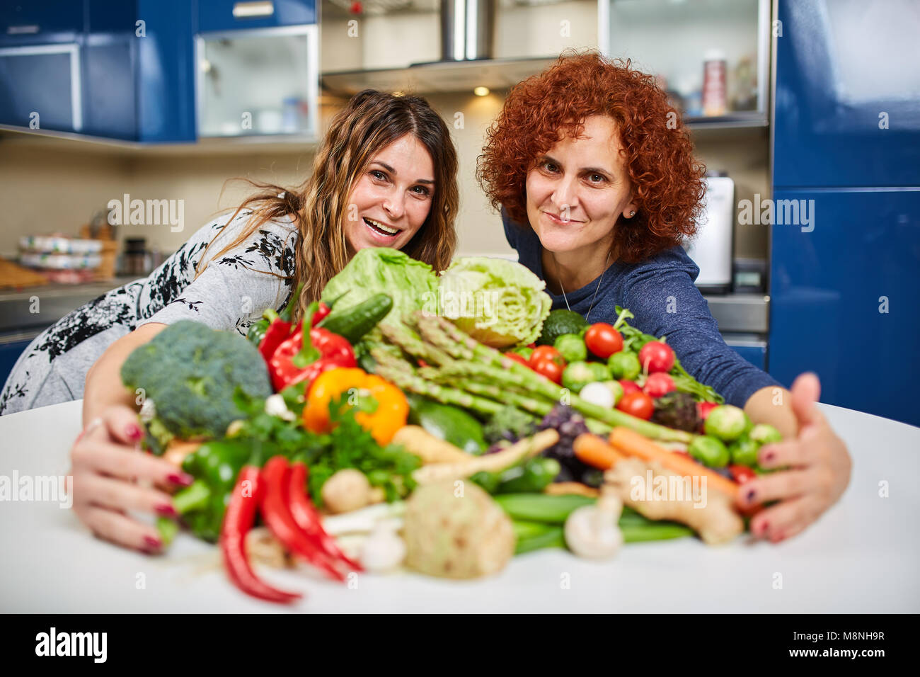 Friends cooking together, having a variety of vegetables on the table ...