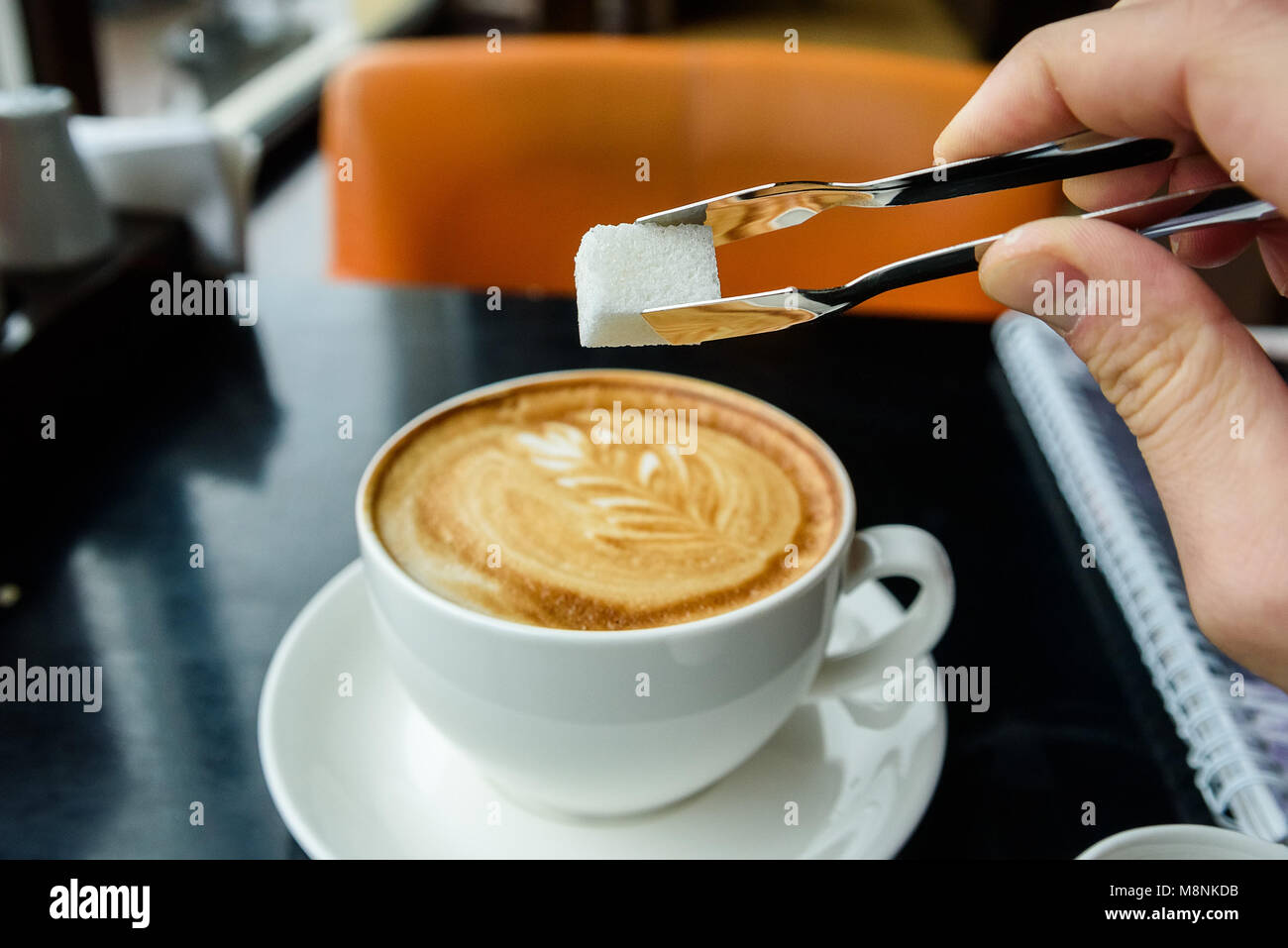 Hand adds lump of sugar to coffee Stock Photo - Alamy