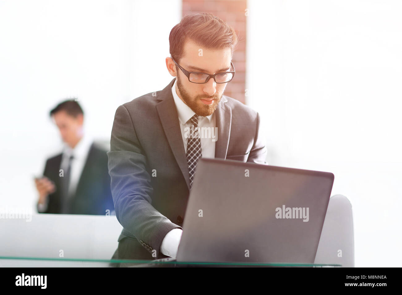 Serious man doing business with a laptop on the office background Stock ...