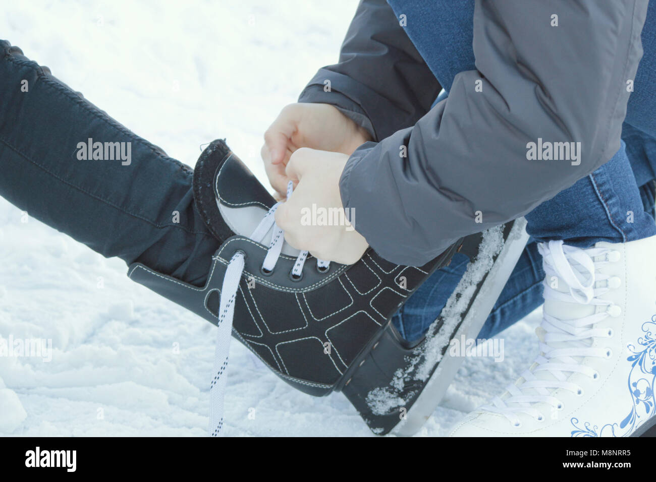 Teen girl wearing skates tying skates another teen Stock Photo - Alamy