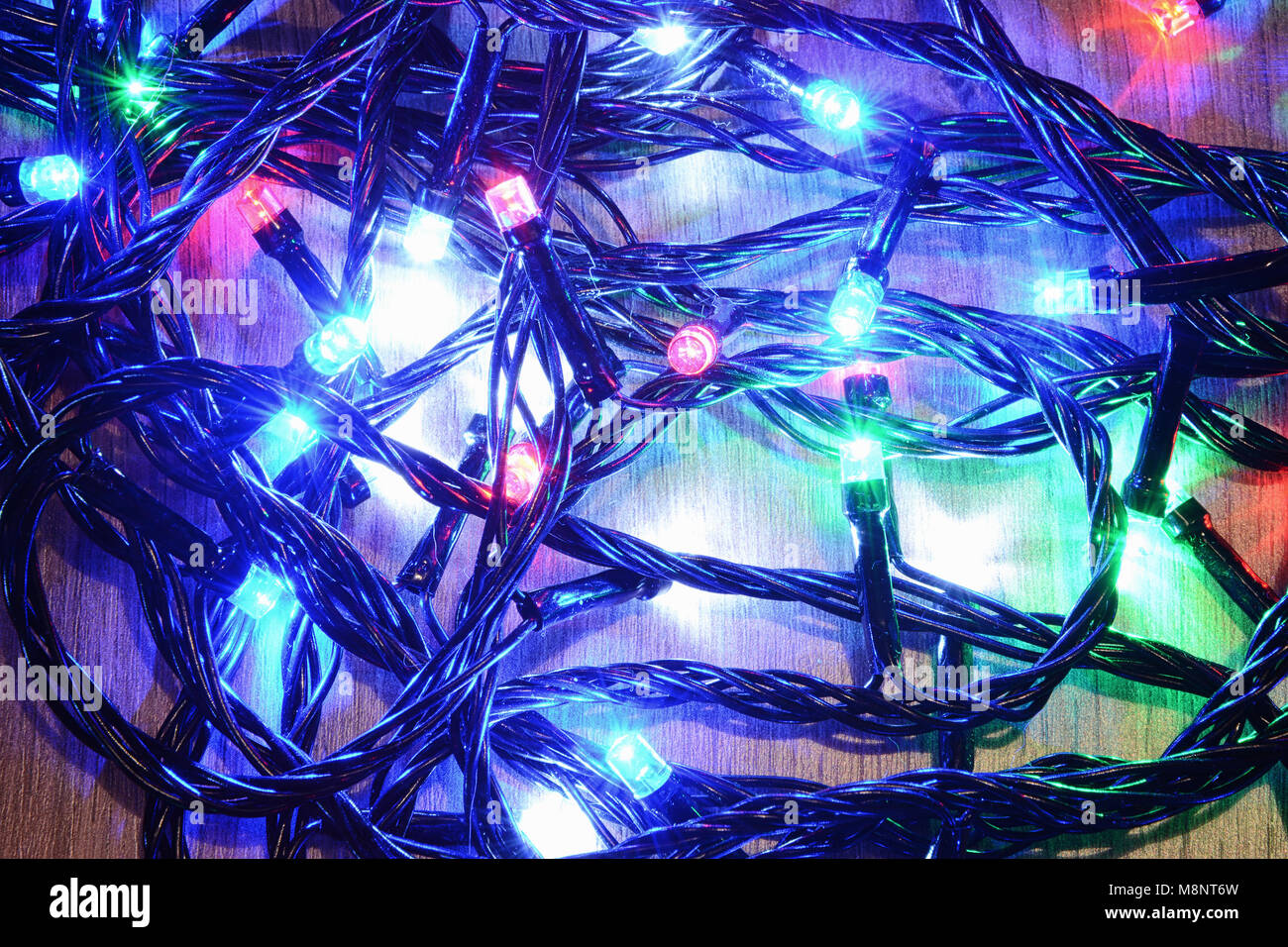 New-year electric garland on a wooden background. Bright bulbs on a ...