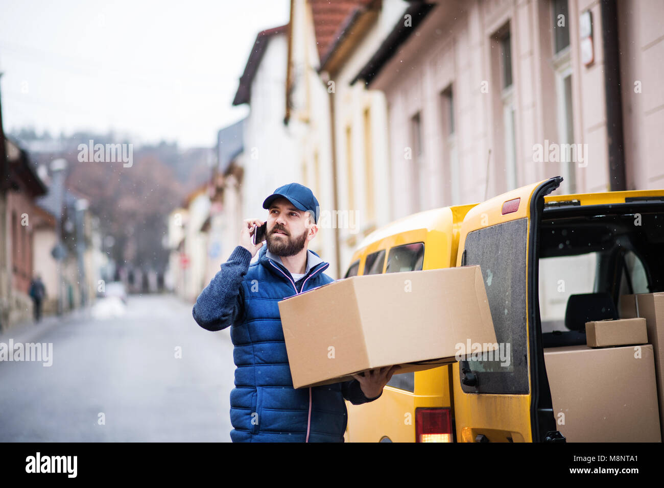 Delivery man with a parcel box on the street Stock Photo - Alamy