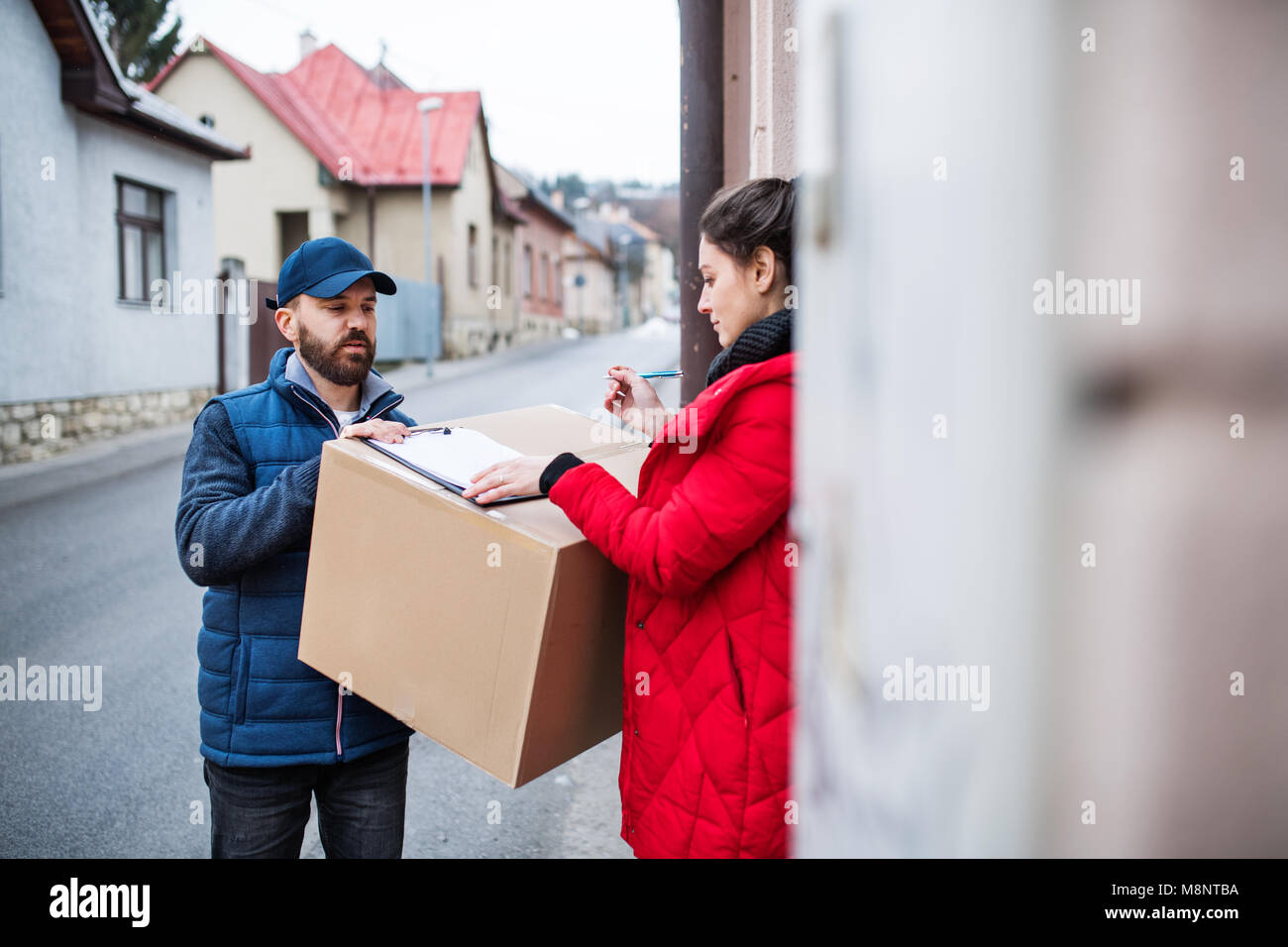 Woman receiving parcel from delivery man at the door Stock Photo - Alamy