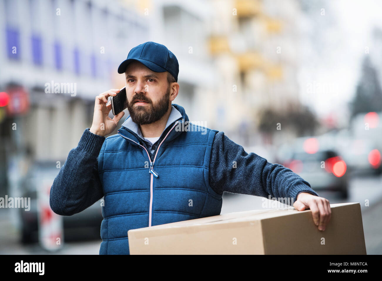 Delivery man with a parcel box on the street Stock Photo - Alamy