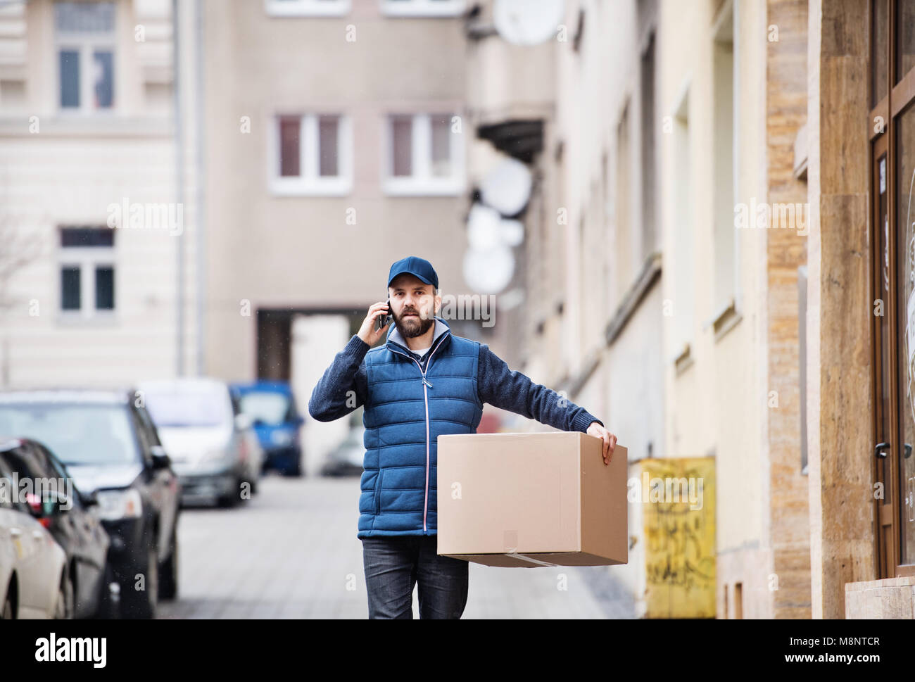 Delivery man with a parcel box on the street Stock Photo - Alamy