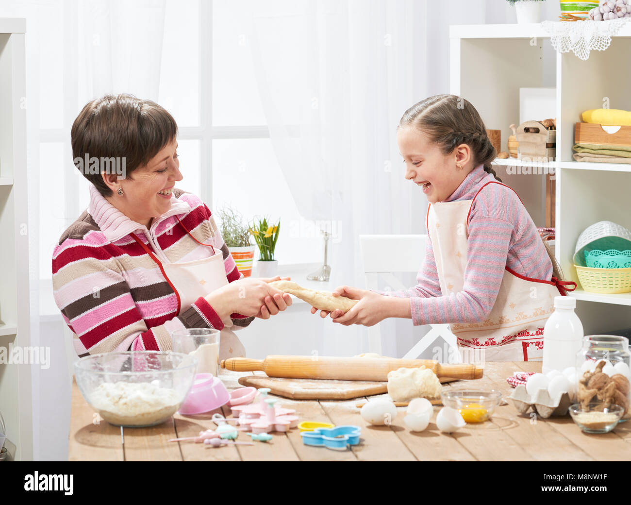 Mother and daughter cooking at home, making the dough for buns Stock ...