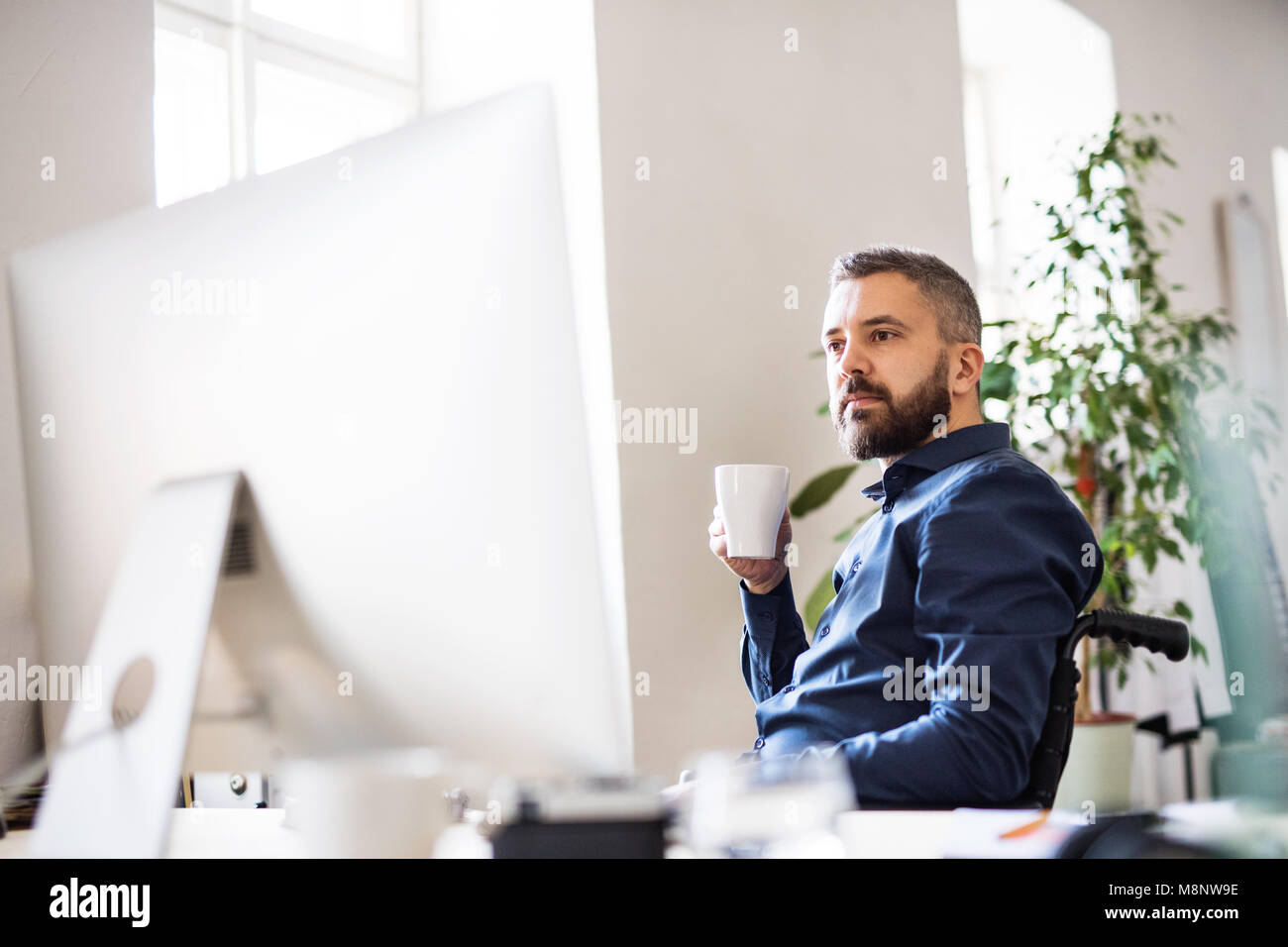 Man sitting desk in wheelchair hi-res stock photography and images - Alamy