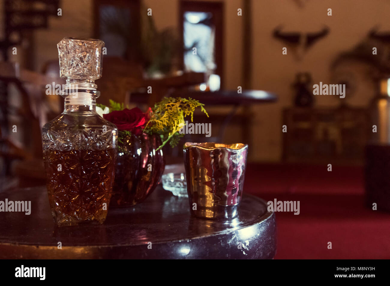 Antique whiskey bottle on top of classic table with candles and roses ...
