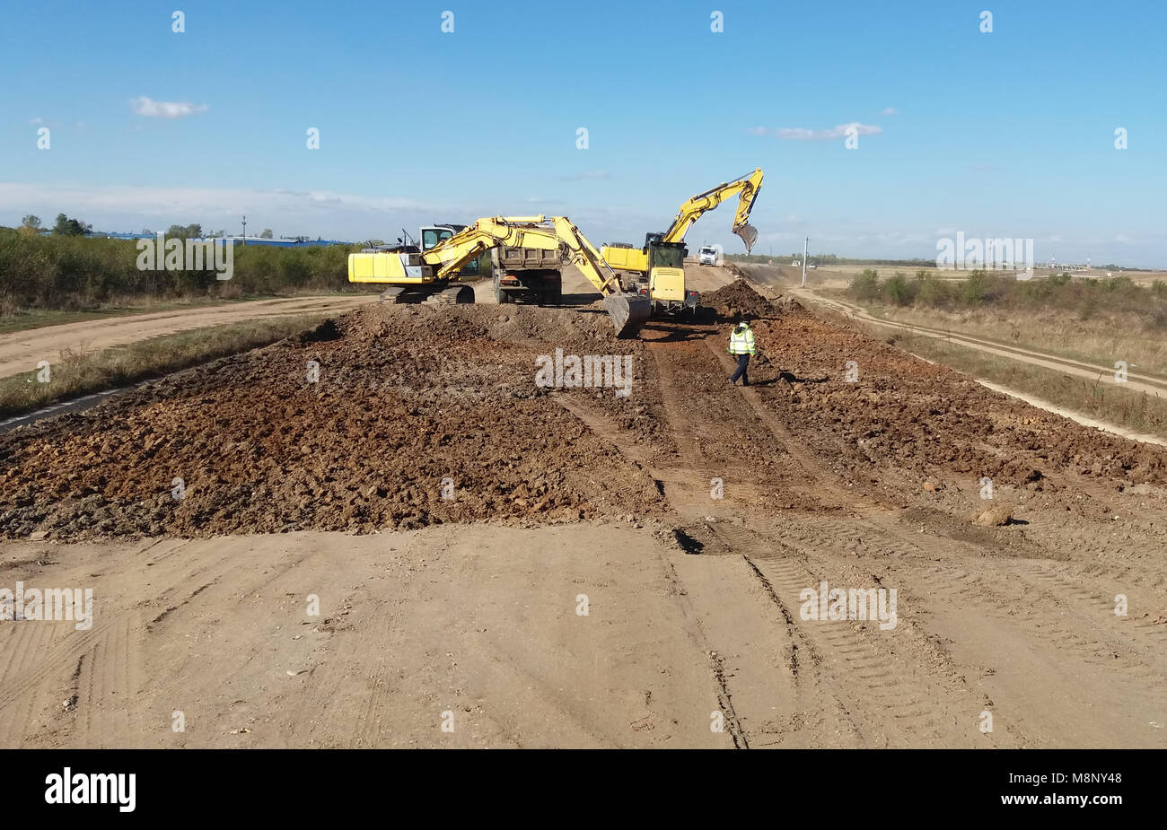 Excavators and truck on construction site Stock Photo - Alamy