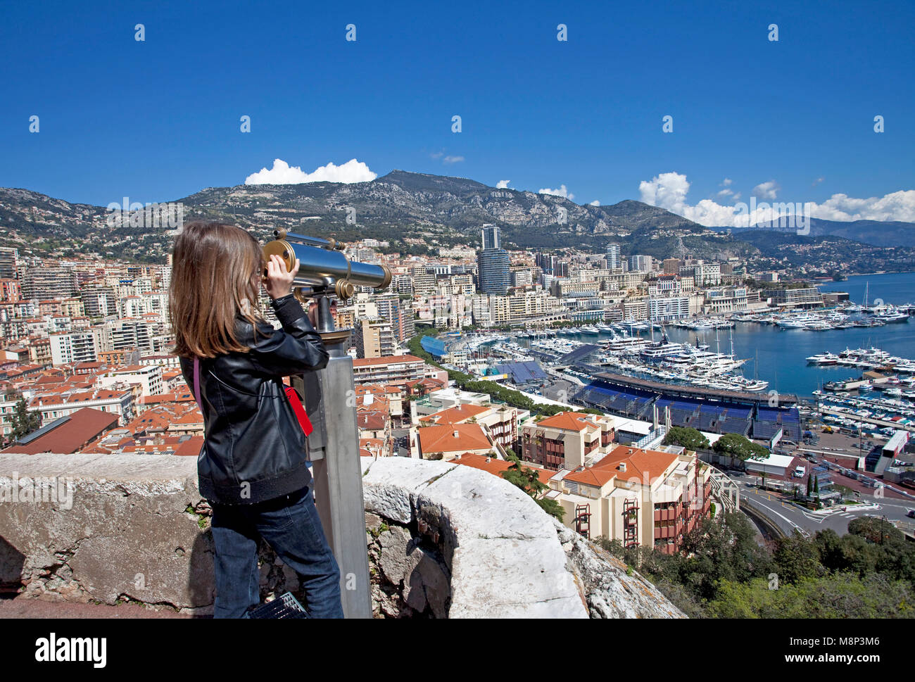 Little girl views Monaco with a telescope from a view point ...