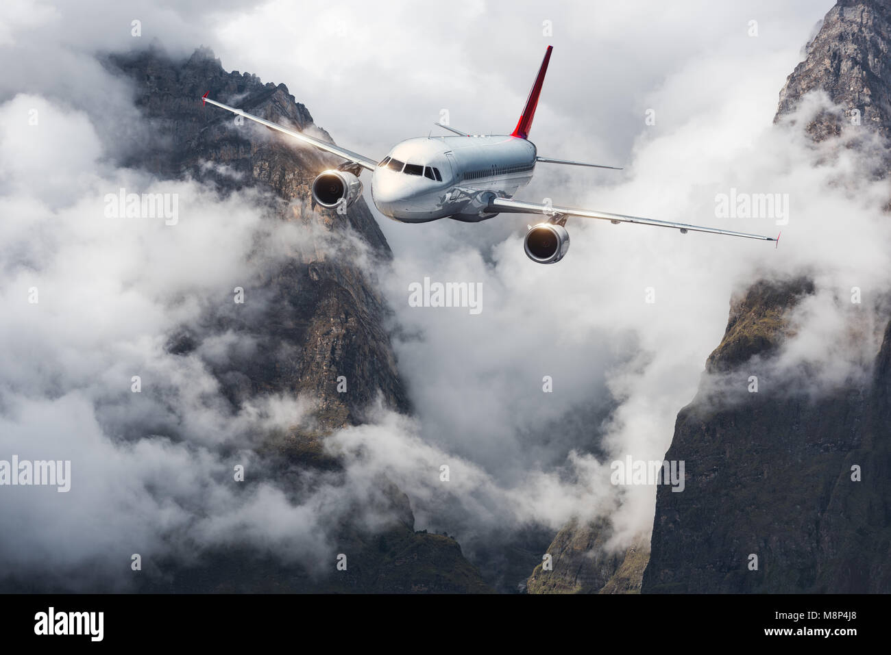 Aircraft, mountains in overcast sky. Airplane is flying in clouds ...