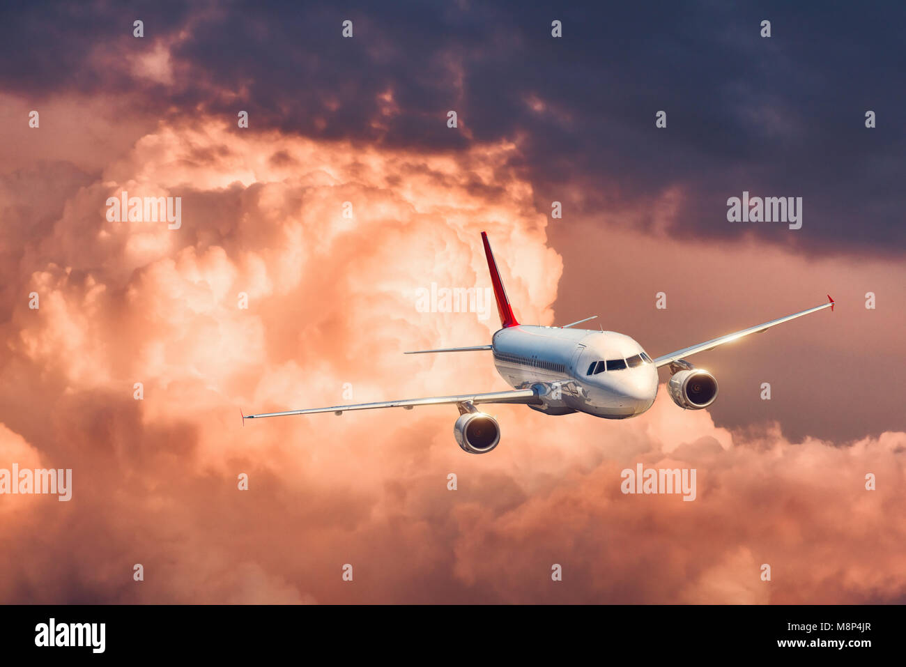 Beautiful airplane is flying in low clouds at colorful sunset. Scene ...
