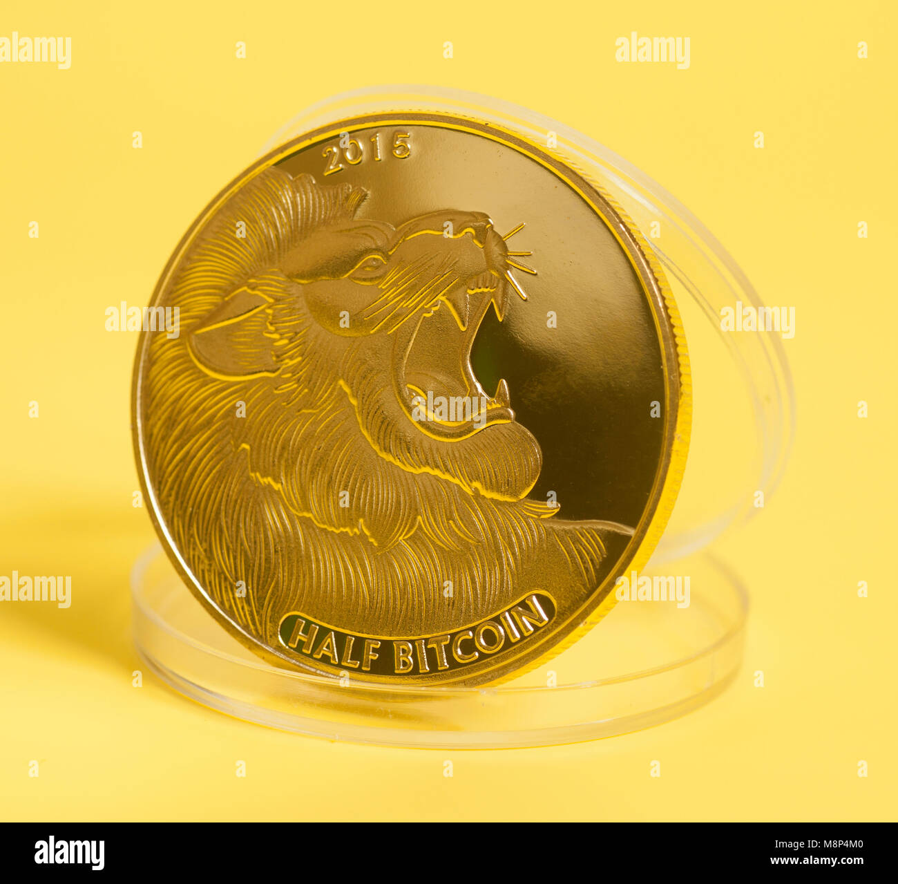 Half bitcoin with lion on a yellow background Stock Photo - Alamy