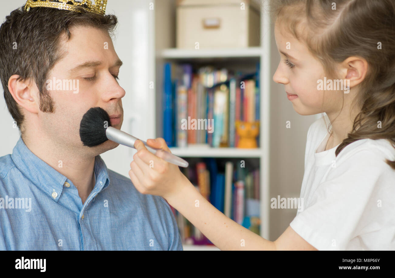 Cute little girl making makeup to her dad Stock Photo - Alamy