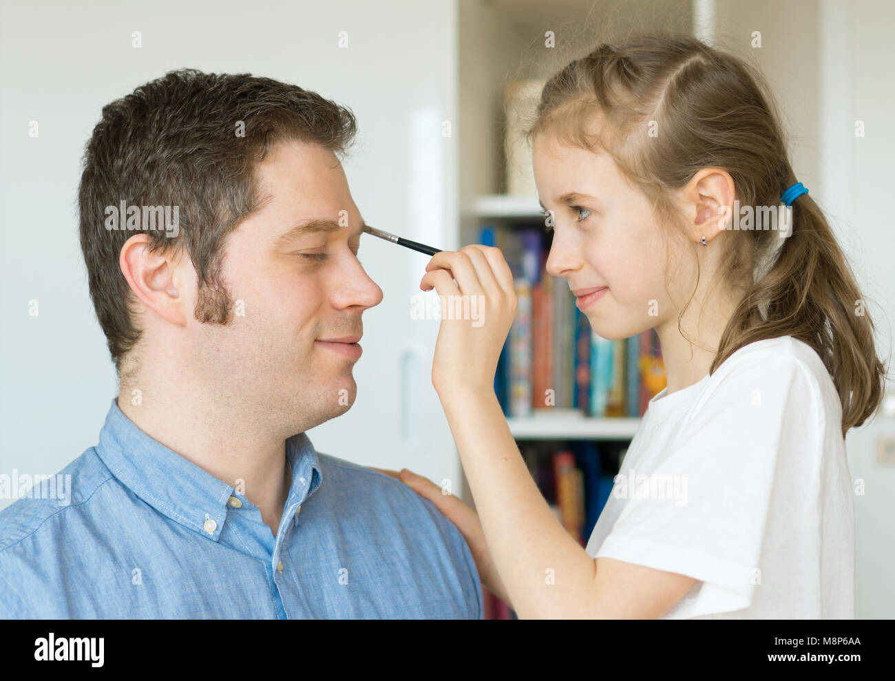 Cute little girl making makeup to her dad Stock Photo - Alamy