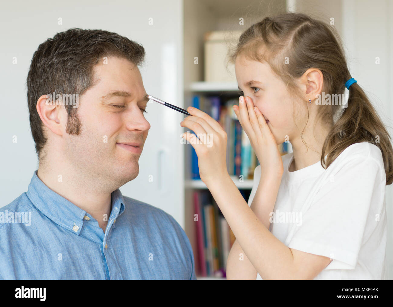 Cute little girl making makeup to her dad Stock Photo - Alamy