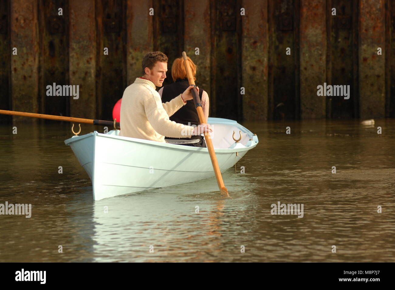 Man and a woman in a rowing boat casting off with oars in hand in ...