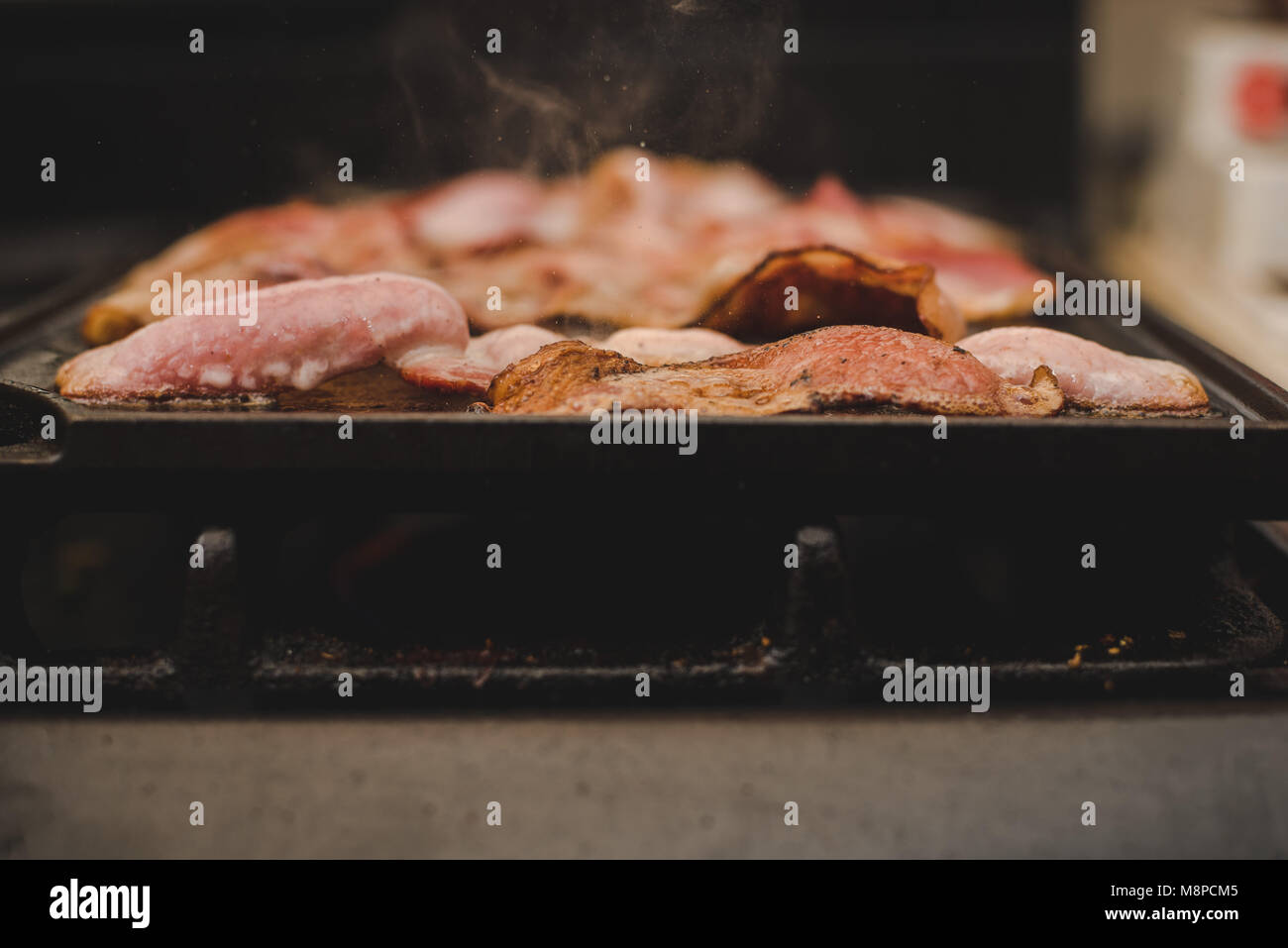 A close up for bacon sizzling on a griddle Stock Photo - Alamy
