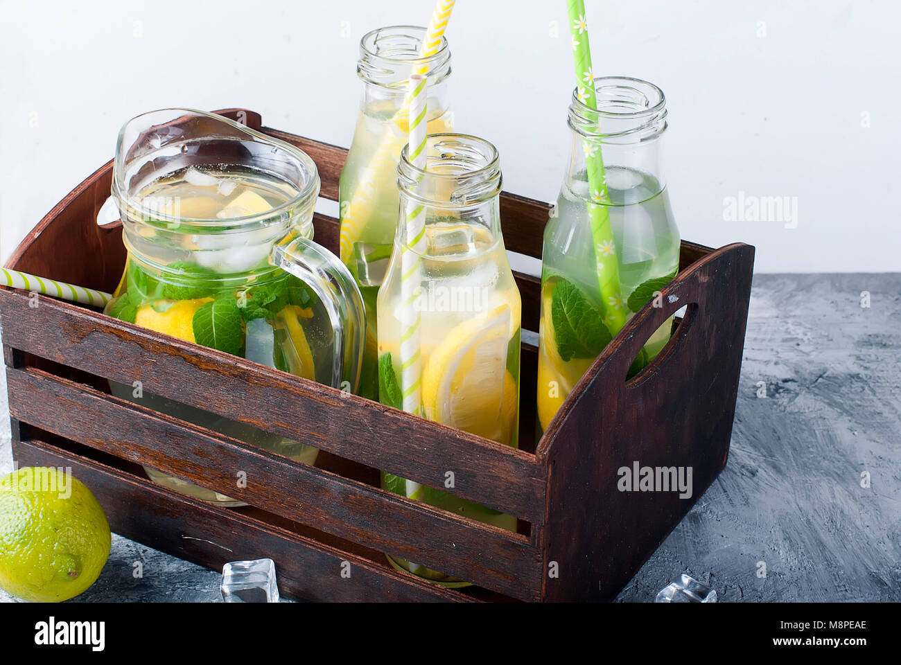 Fresh homemade lemonade in glass jug and bottles with ice and mint ...