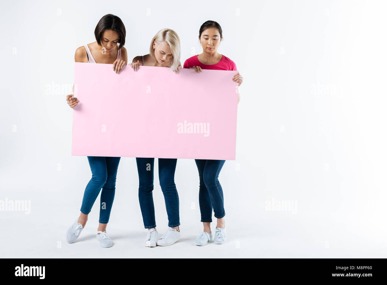 Nice young women looking at the poster Stock Photo - Alamy