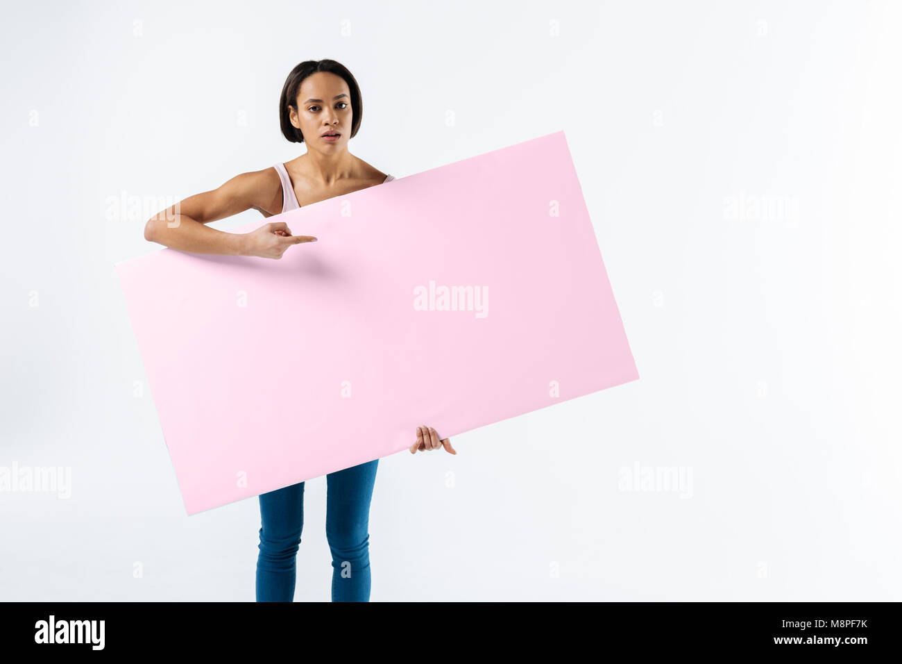 Pleasant young woman pointing at the poster Stock Photo - Alamy