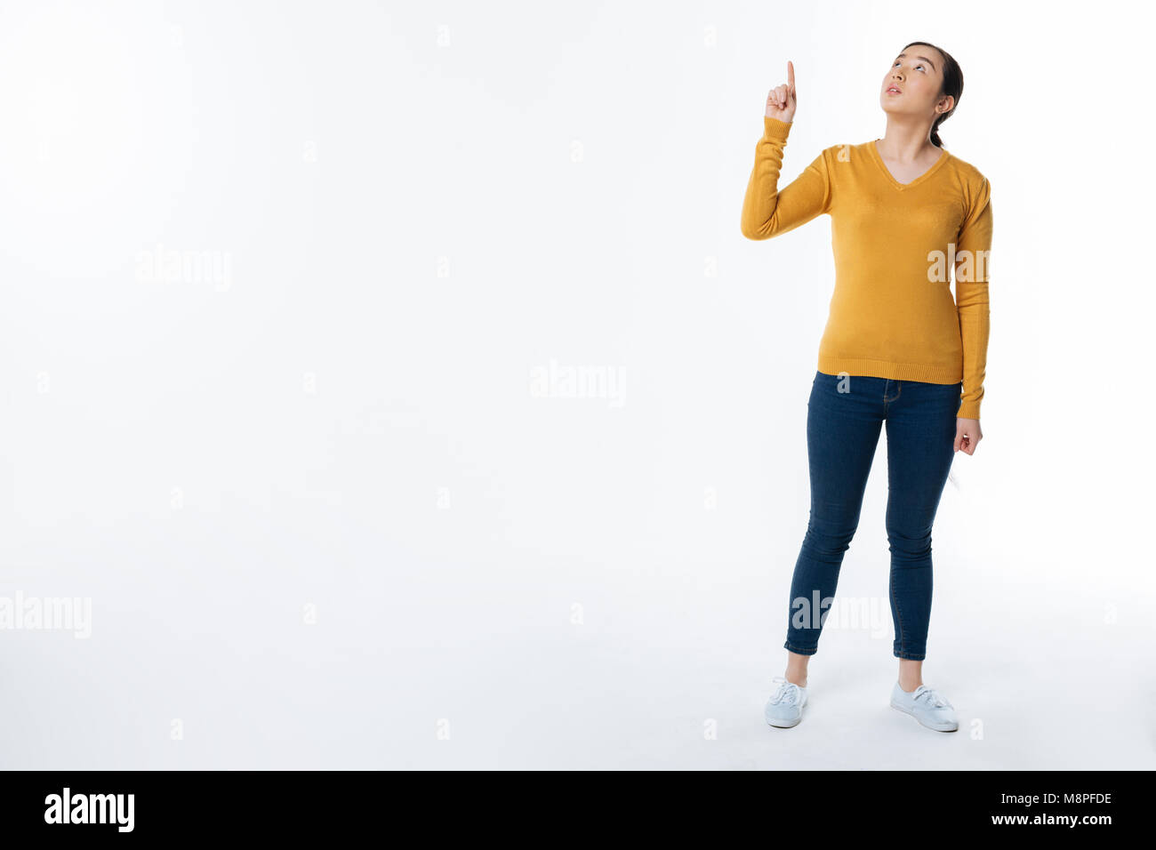 Serious young woman standing against white background Stock Photo - Alamy