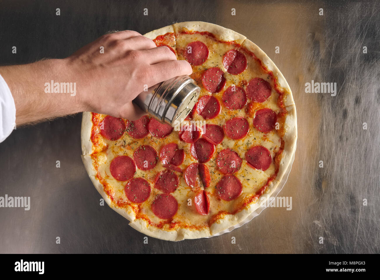 sprinkling with dry spices ready pizza Stock Photo - Alamy