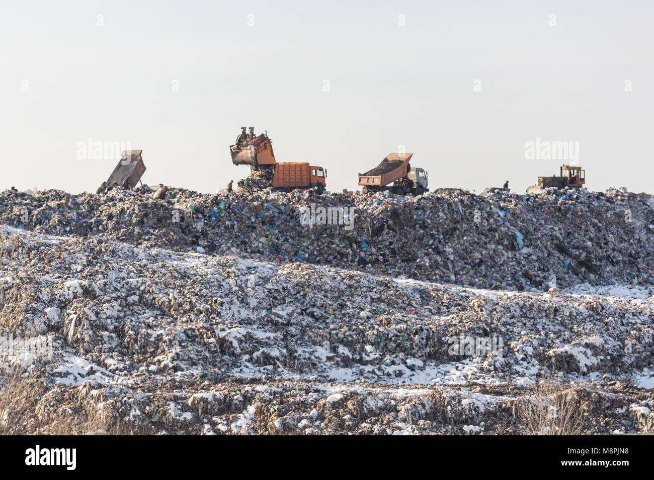 Dump trucks unloading garbage over vast landfill. Environmental ...