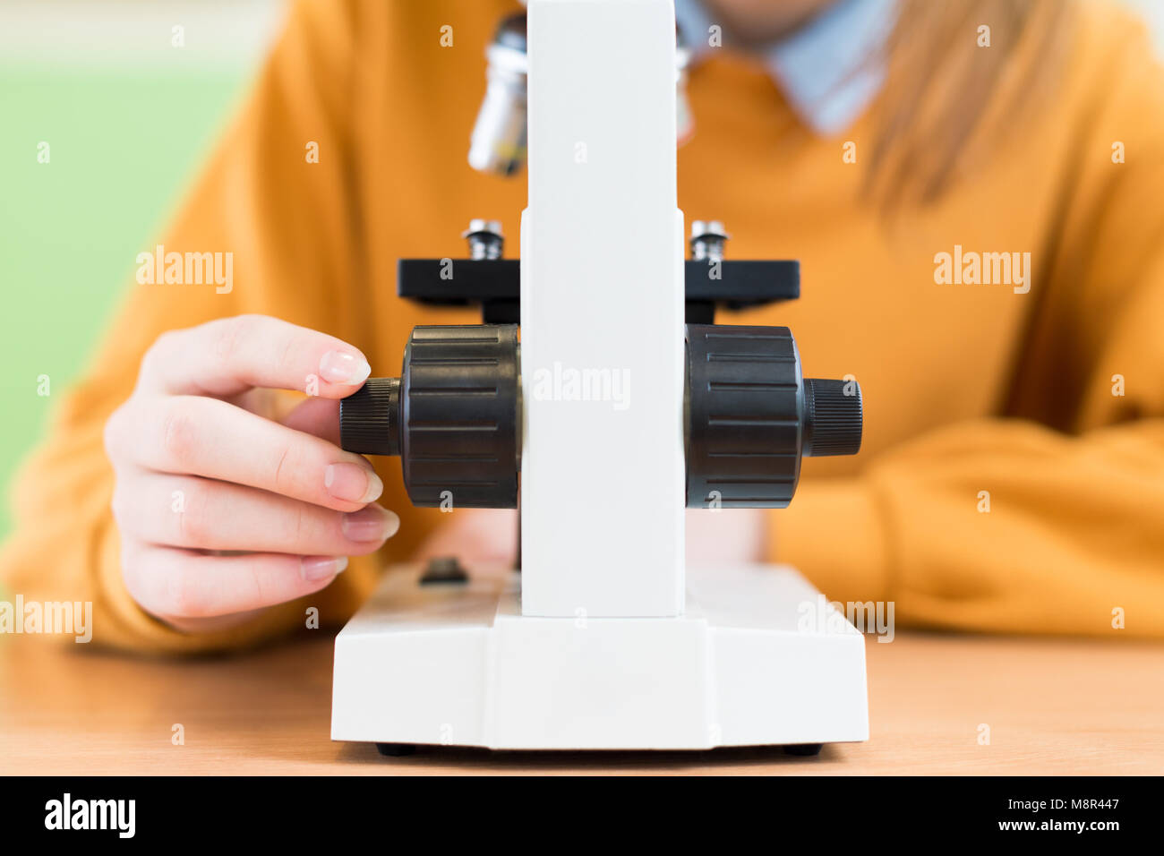 High School female student in biology class. Student using microscope ...