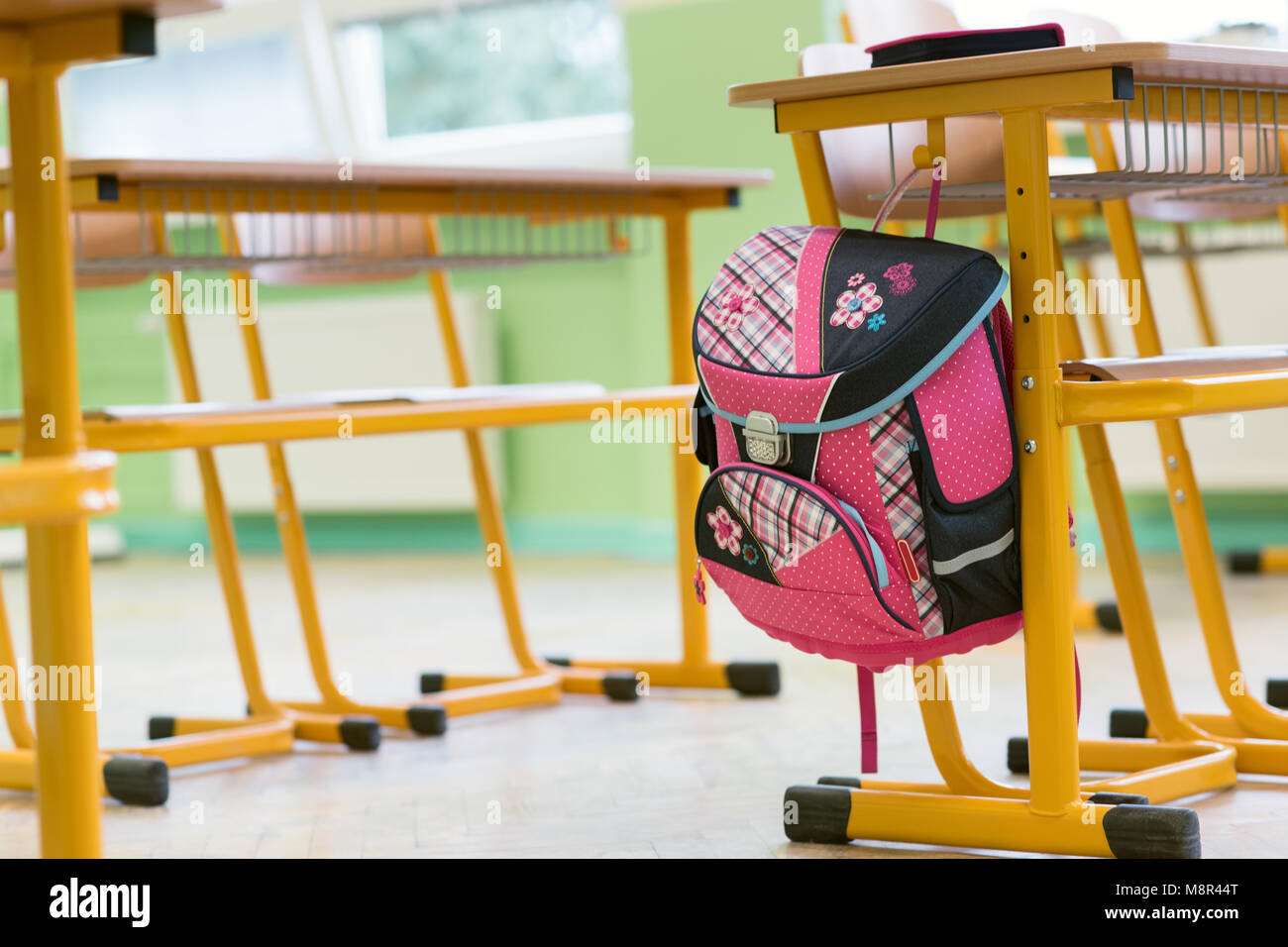 Pink girly school bag and pencil case on a desk in an empty classroom ...